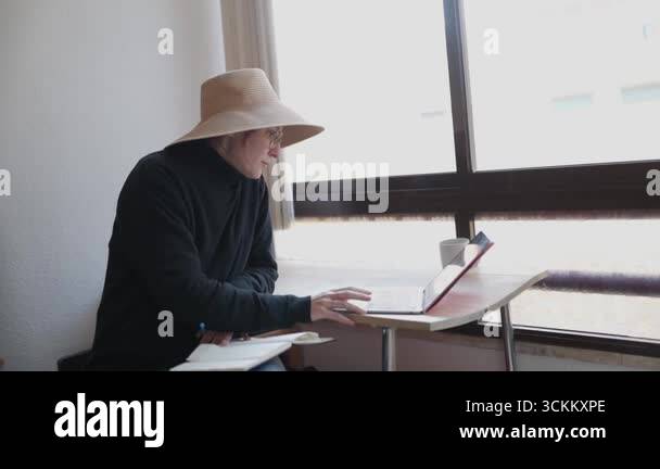 Focused writer wearing a hat concentrating on writing a novel on a ...