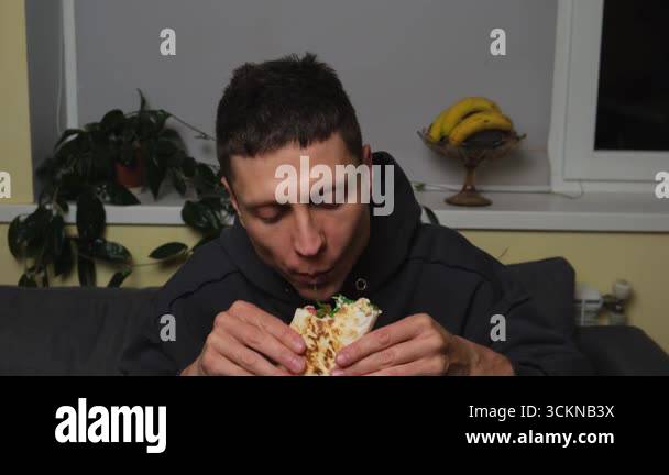 Man eating vegetarian lavash wrap with fresh vegetables and cheese in ...