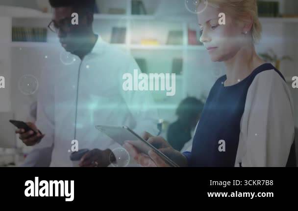 Man scrolling phone and woman tapping tablet activating floating data graphics for tech teamwork ...