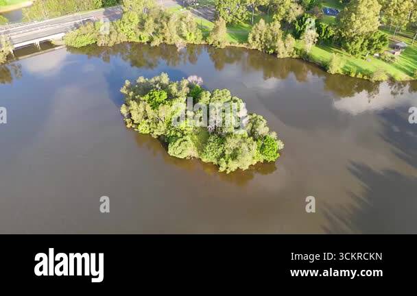 Drone footage captures a small, verdant island in a tranquil canal on ...