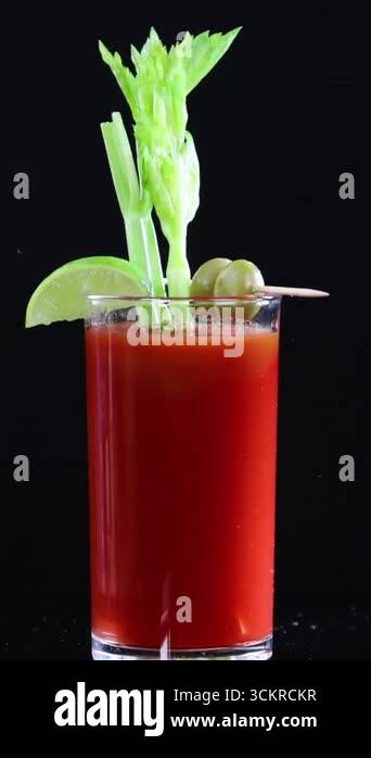 Bloody Mary cocktails garnished with celery, olives, and lime against a ...