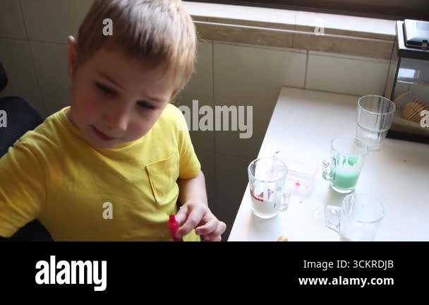 Curious boy exploring color mixing with red and green paints, creating ...