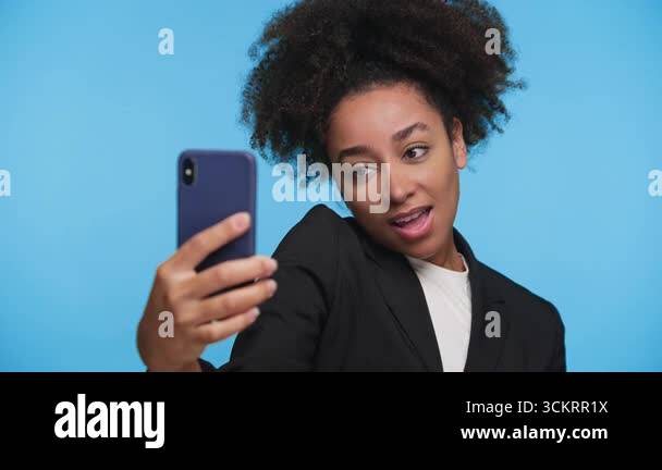 Young professional woman striking a fun pose while taking a selfie with ...