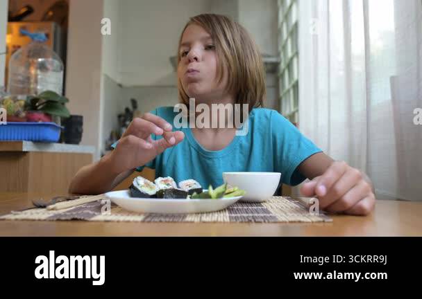 Young child eating sushi at home kitchen table. Cozy atmosphere ...
