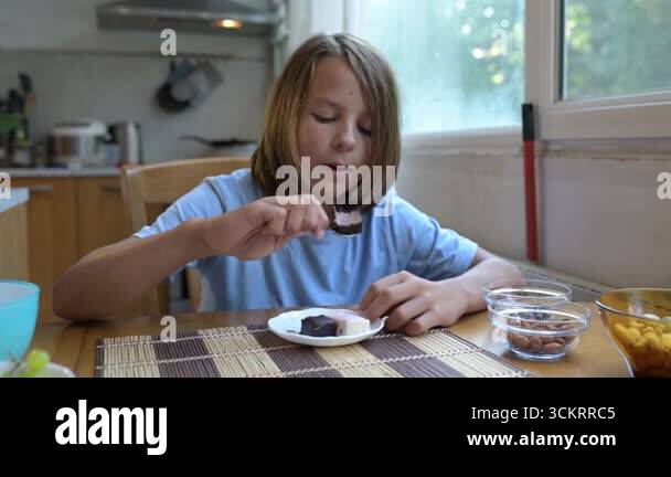 Young child eating a curd dessert at home kitchen table. Relaxed ...