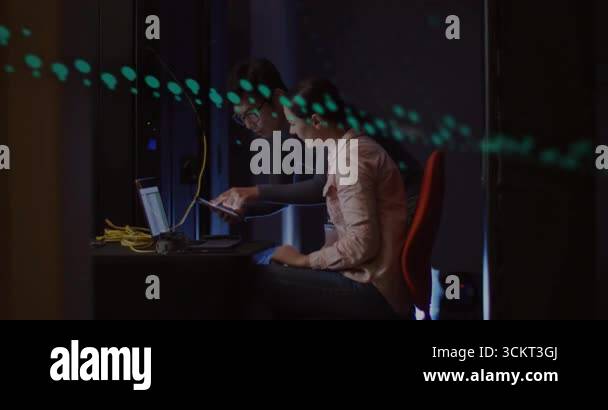 Woman plugging LAN cable into laptop, coding with man observing ...