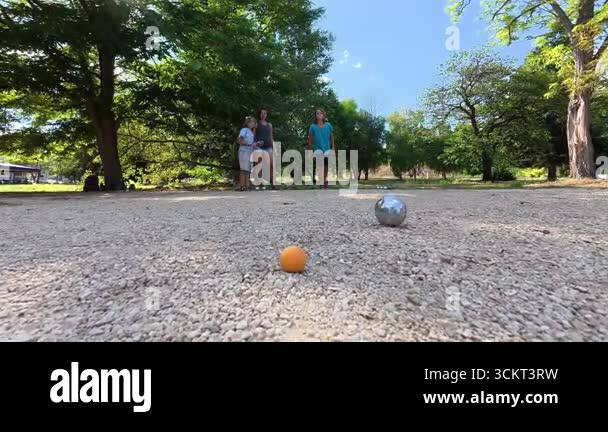 Family playing petanque together in the park. Adults and children take ...