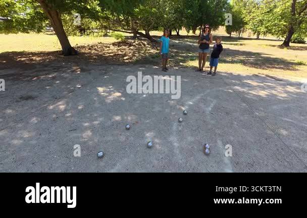 Family playing petanque together in the park. Adults and children take ...
