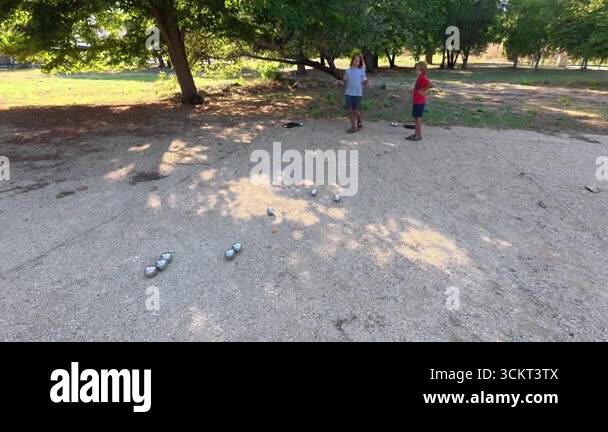 Two boys playing petanque outdoors on a sunny day. Children take turns ...