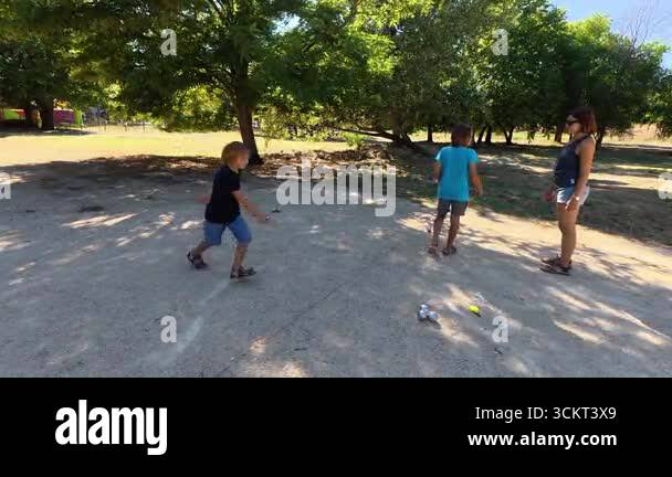 Family playing petanque together in the park. Adults and children take ...