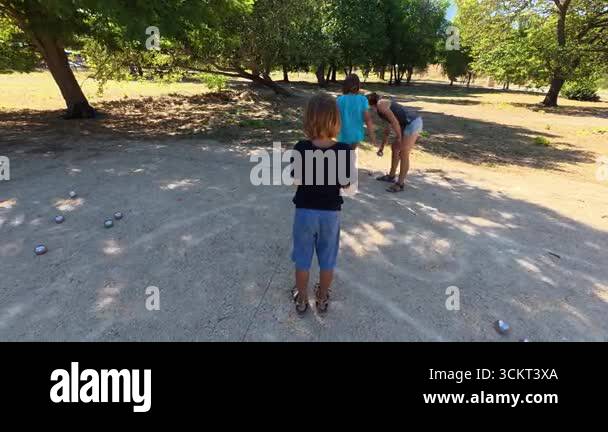 Family playing petanque together in the park. Adults and children take ...