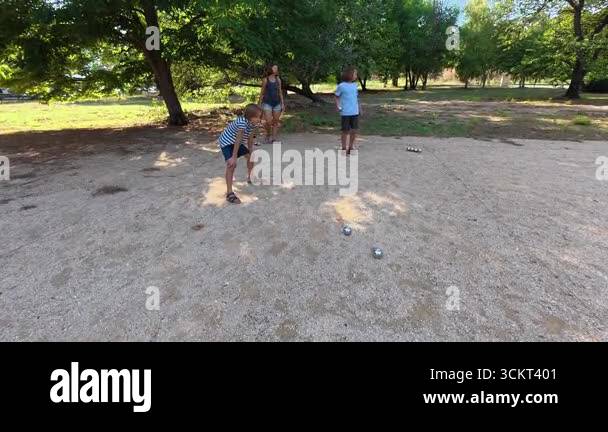 Family playing petanque together in the park. Adults and children take ...