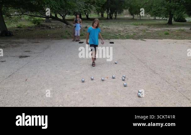 Family playing petanque together in the park. Adults and children take ...