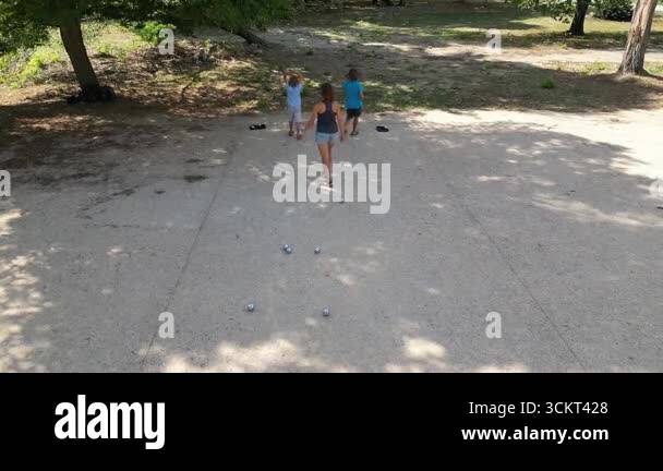Family playing petanque together in the park. Adults and children take ...