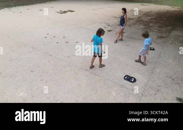 Family playing petanque together in the park. Adults and children take ...