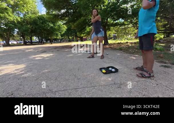 Family playing petanque together in the park. Adults and children take ...