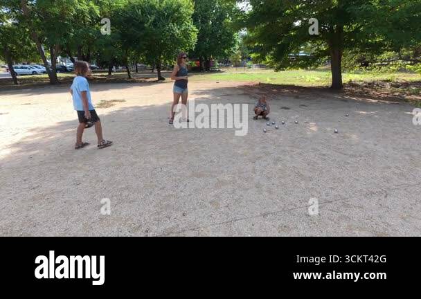Family playing petanque together in the park. Adults and children take ...