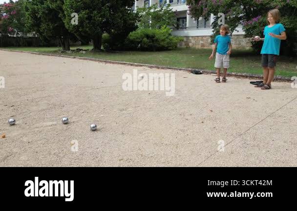 Two boys playing petanque outdoors on a sunny day. Children take turns ...