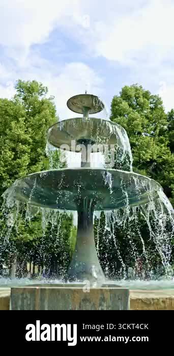 Large fountain in a city park. Water flows down a relief fountain ...