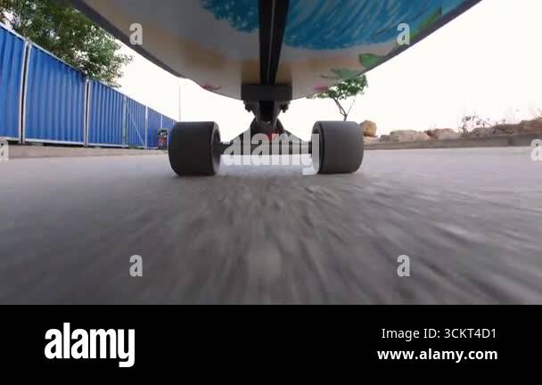 Low angle POV shot of skateboard rolling on asphalt, close up of wheels ...