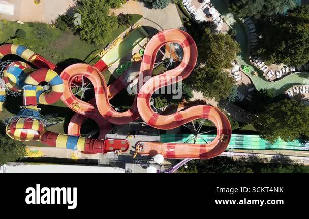 Aerial view of colorful twisting water slides with people riding ...