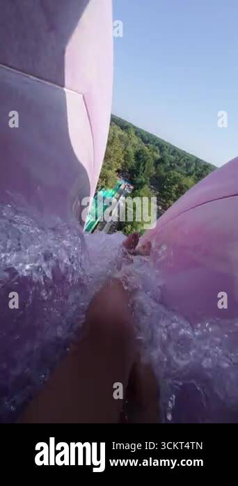 Child splashing down from a tall, vertical water slide at a water park ...