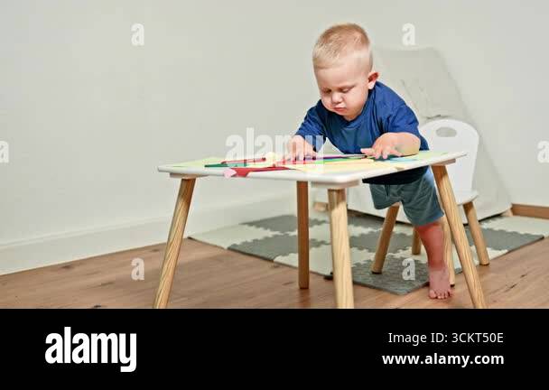 Cheerful toddler learns to draw with colored pencils. Child develops ...