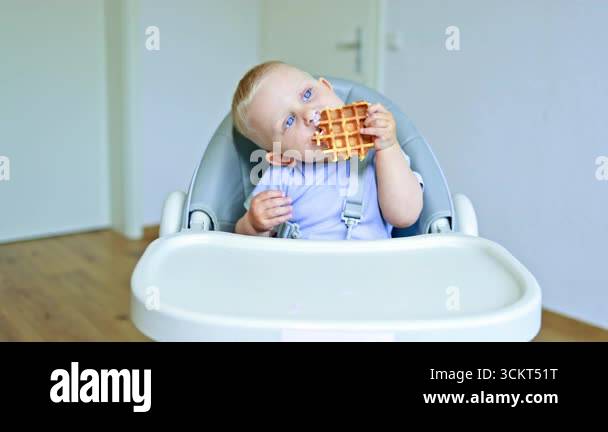 Cute baby sitting and eating homemade Belgian waffles. Child eating ...