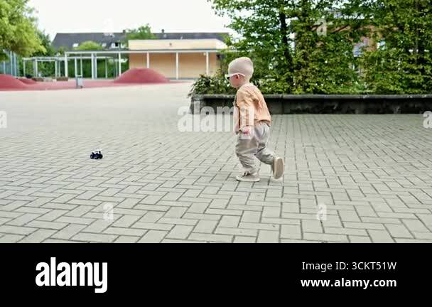 Toddler in joggers and t-shirt running in city park on playground ...
