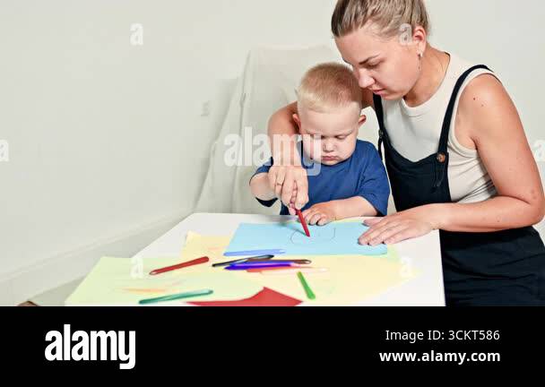Mom teaches her little son to draw with pencils. Happy mother and her ...