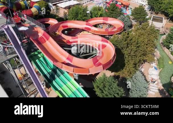 Aerial view of colorful twisting water slides with people riding ...
