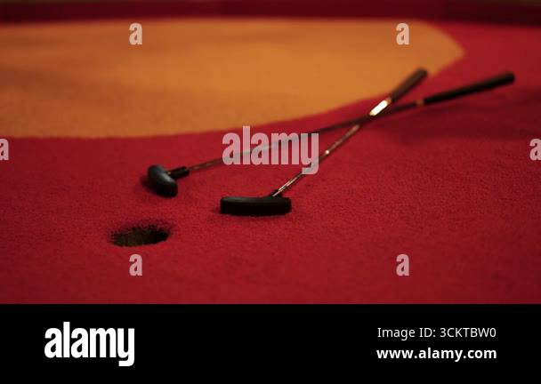 A red golf ball narrowly misses the hole on a miniature golf course ...