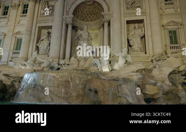Trevi Fountain illuminated at night with statues and flowing water in ...