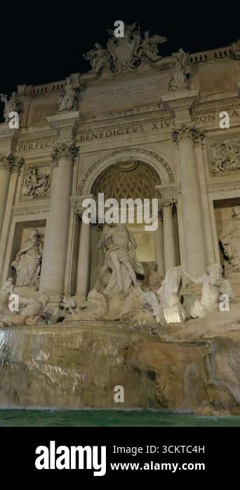 Vertical night view of Trevi Fountain with illuminated sculptures and ...