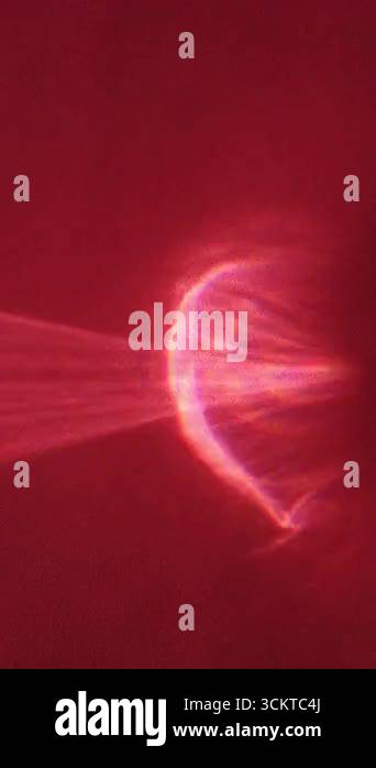 Light beam radiating intense lens flare against vivid red background ...