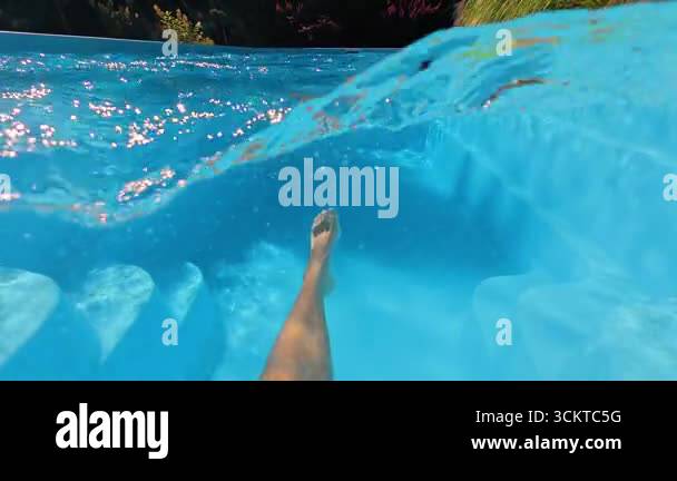 Swimming pool with active counterflow system, underwater view of legs ...