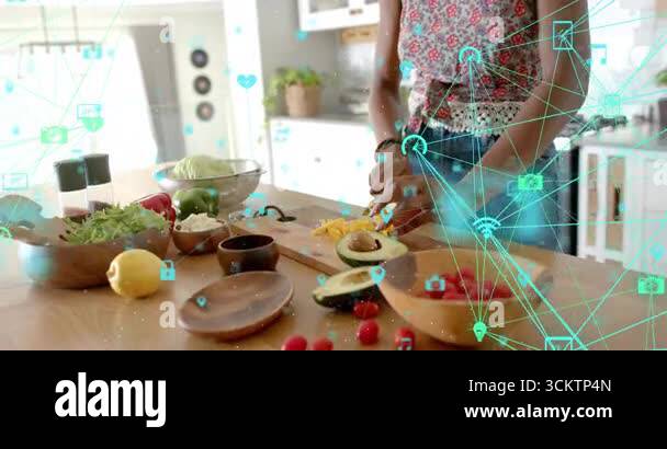Close-up woman halving avocado, chopping pepper on wooden board, activating smart kitchen icons ...