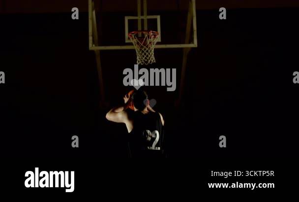 Basketball player holding ball at chest trying to score shooting at hoop with floating hearts ...