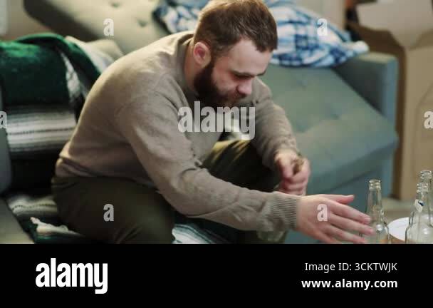 Portrait frustrated man drink beer sit on sofa feel stress depressed ...