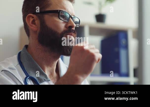 Face of concentrated Caucasian doctor in glasses looking closely at ...