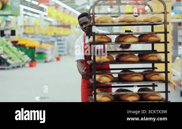Close up handsome young african american man seller puts the bread on ...