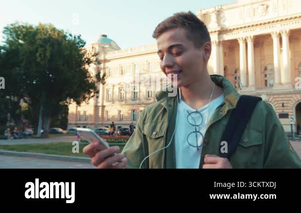 handsome young man use phone speak on mobile in headphone look around ...