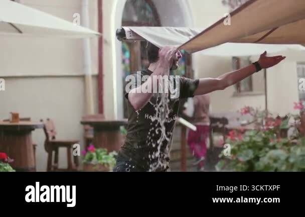 Handsome young man doing something in the rain on the street caucasian ...