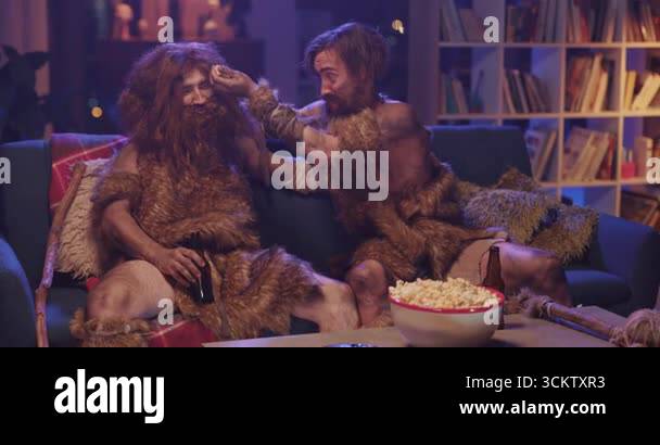 Prehistoric couple of wild people in fur clothes drinking beer throwing ...
