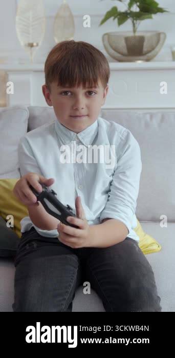 A young boy is happily immersed in gaming on his console, sitting ...