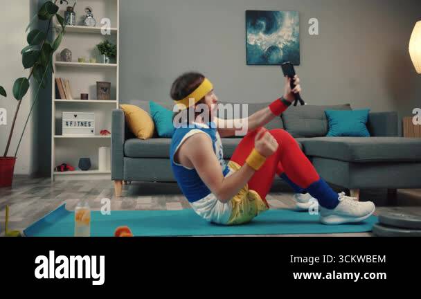 Bearded young man recording fun video with exercise on smartphone for sport vlog. Unsporting ...