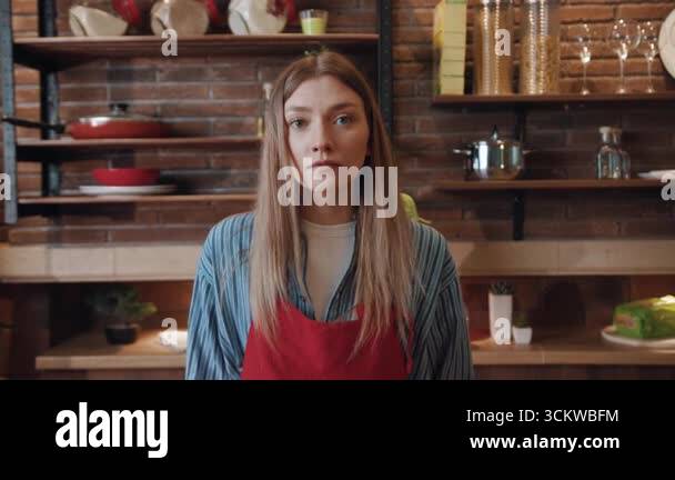 Amazing portrait of beautiful young woman looking at camera cooking ...
