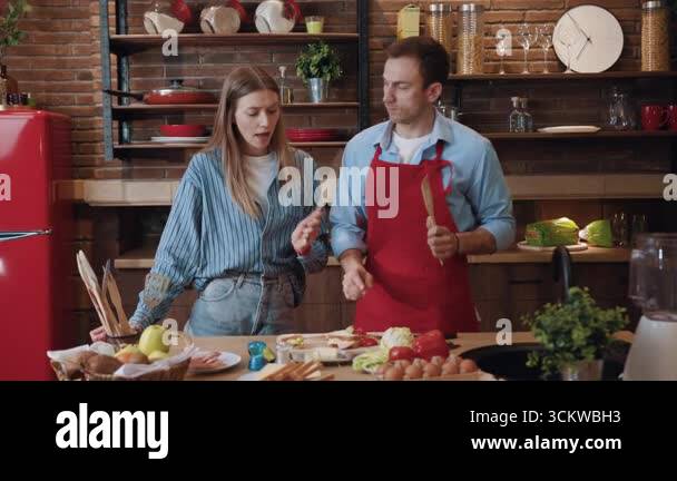 Funny cheerful married couple cooking lunch together dancing into music ...
