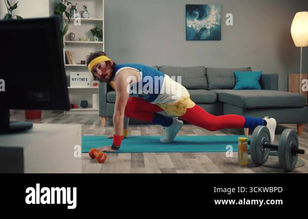 Handsome concentrated sportsman in retro outfit training abs at home ...