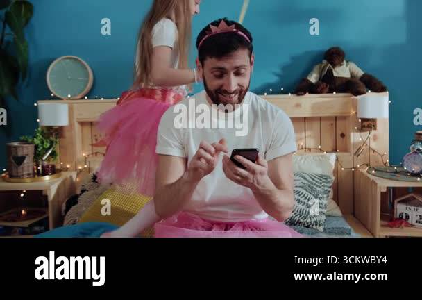 Sociable smiling young man father dressed like princess using a ...